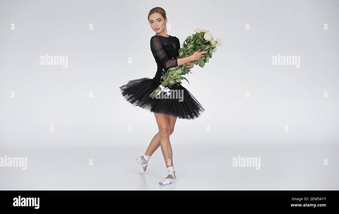 young ballerina holding roses and performing classical ballet dance on ...