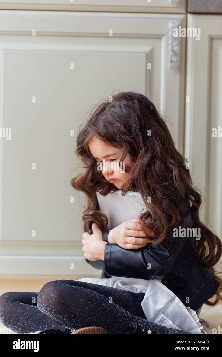 Little girl hugs her tablet computer while sitting on floor, isolated ...