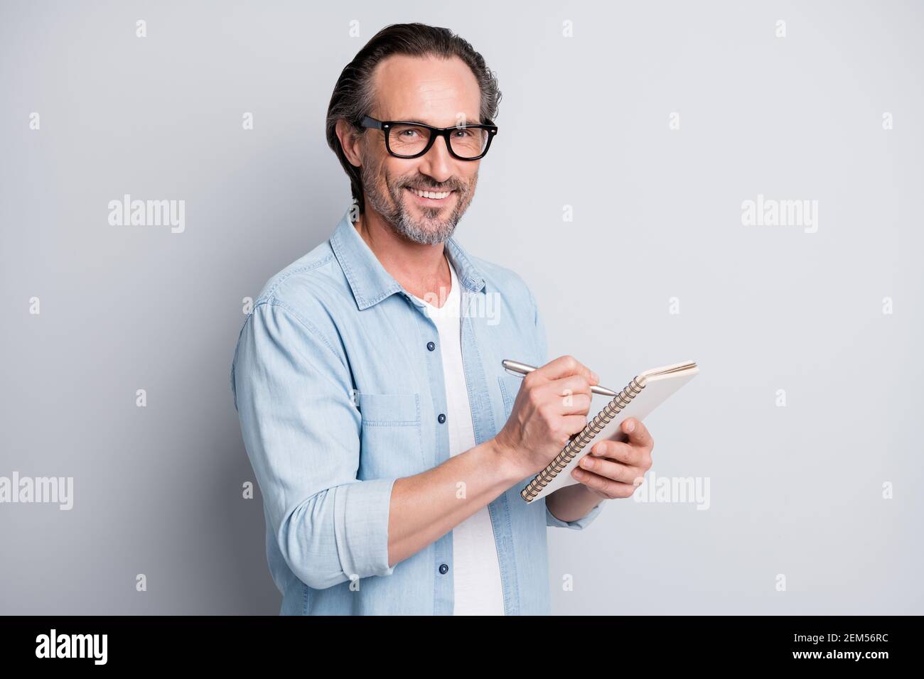 Portrait of handsome clever cheerful mature man writing notes planning ...