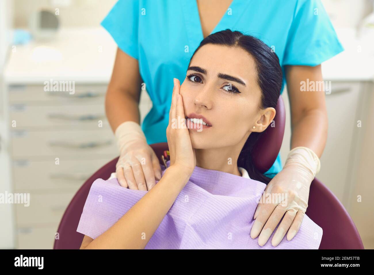 Worried woman patient with toothache touching cheek in dental clinic ...