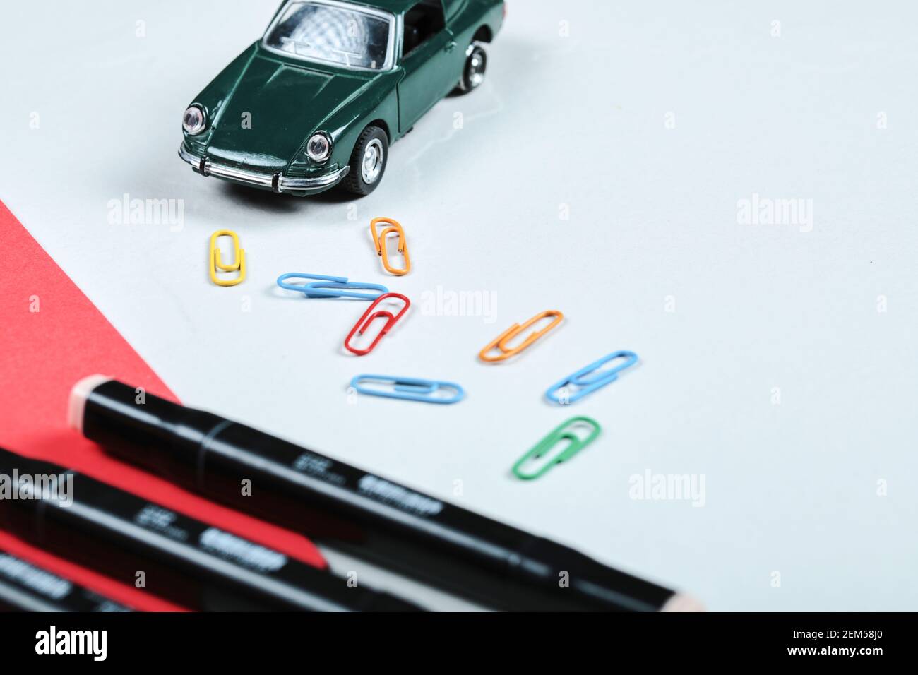 Colorful pencils, clips, red paper and toy car on white background ...