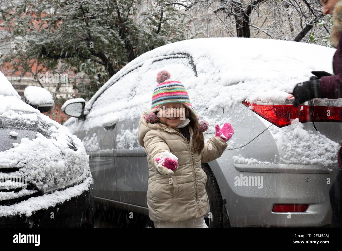 Cute little girl catching snowflakes with her hand. Cute boy playing in ...