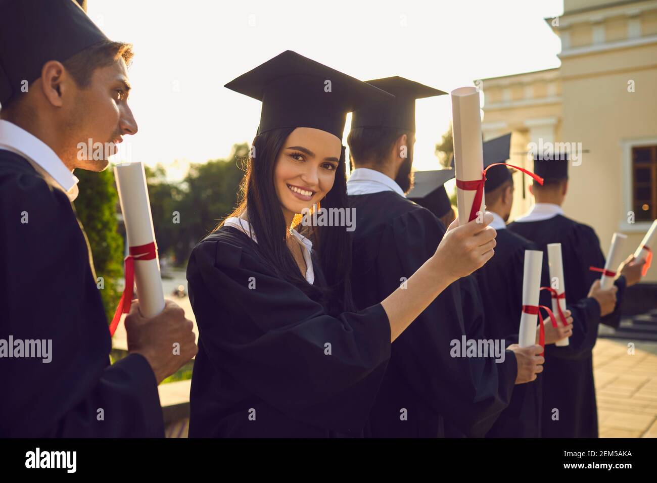 Smiling pretty girl student university graduate holding diploma with ...