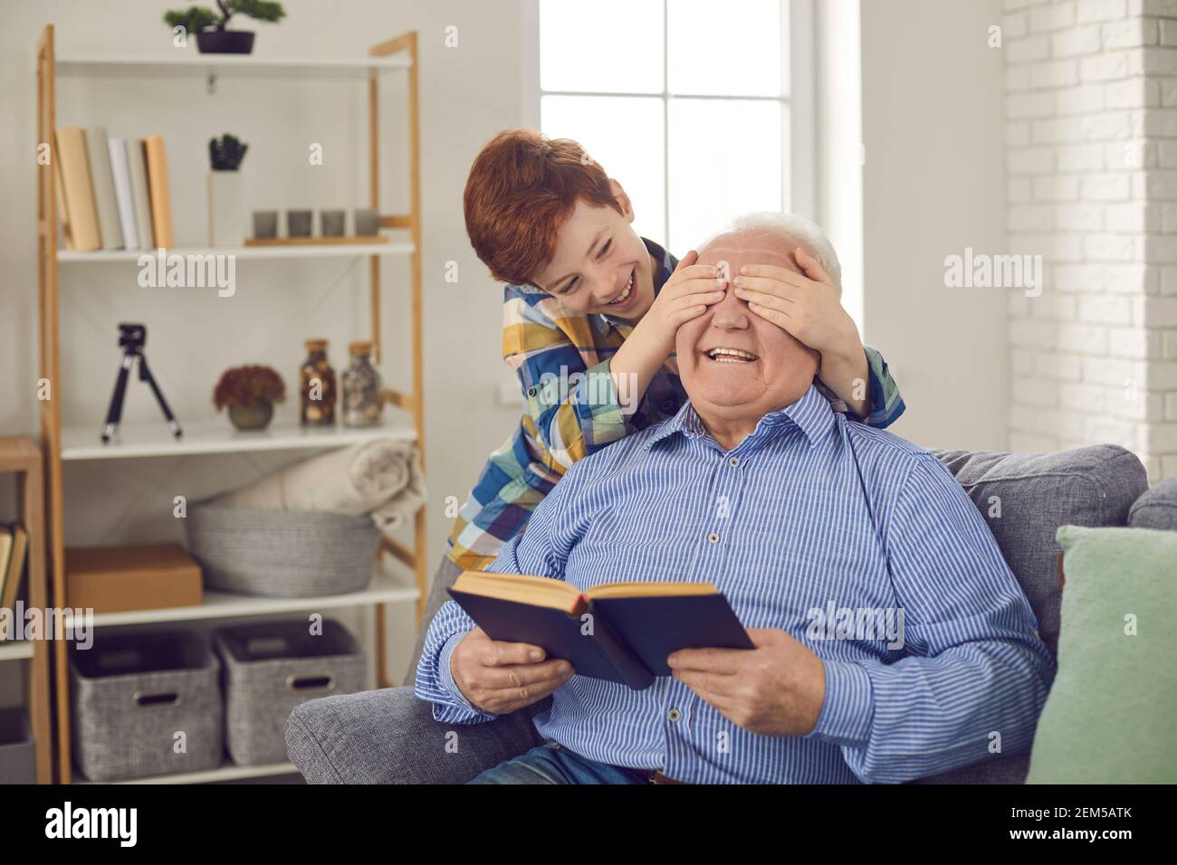 Happy smiling little grandson covers grandfather's eyes and plays Guess ...