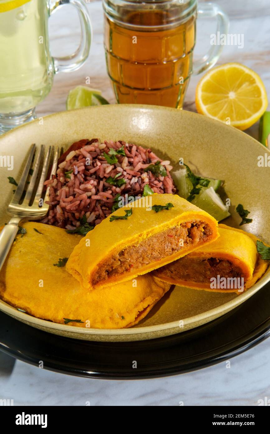 Spicy Jamaican beef turnovers with cilantro garnish and purple rice ...