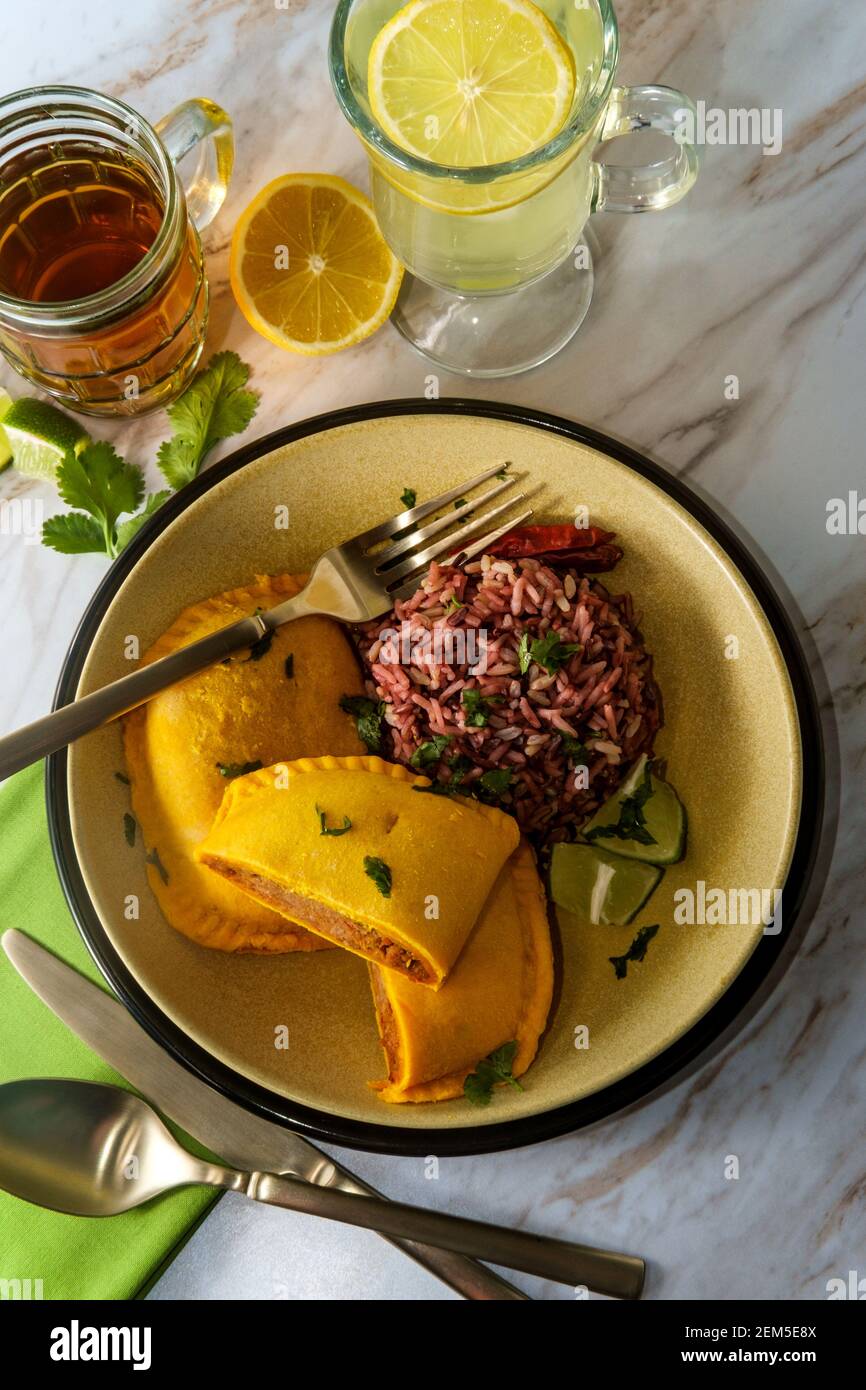 Spicy Jamaican beef turnovers with cilantro garnish and purple rice ...