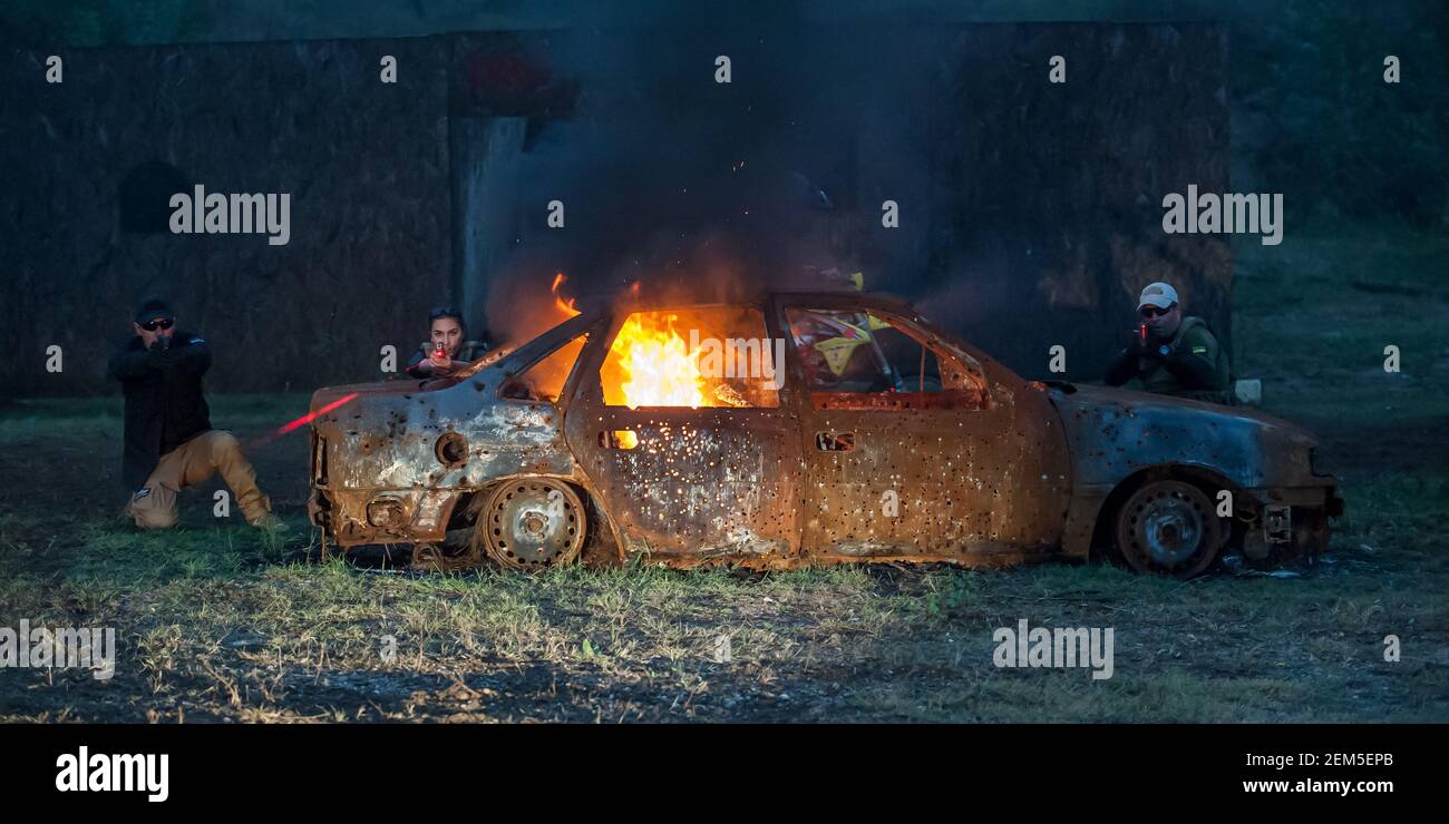 Army soldier hiding behind burning car shooting from machine gun ...