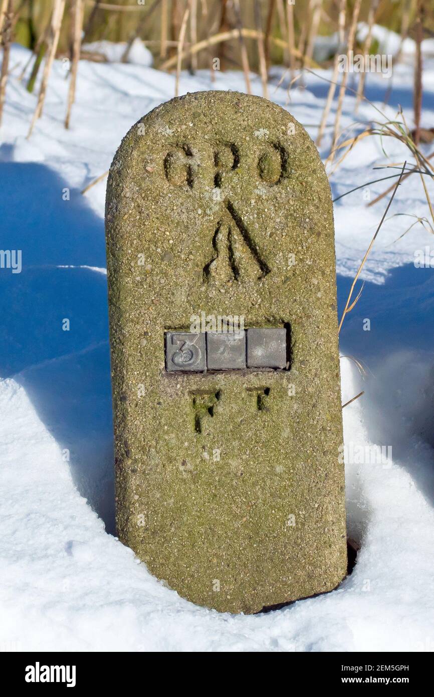 An old UK GPO concrete sign post telling engineers how far, in feet ...