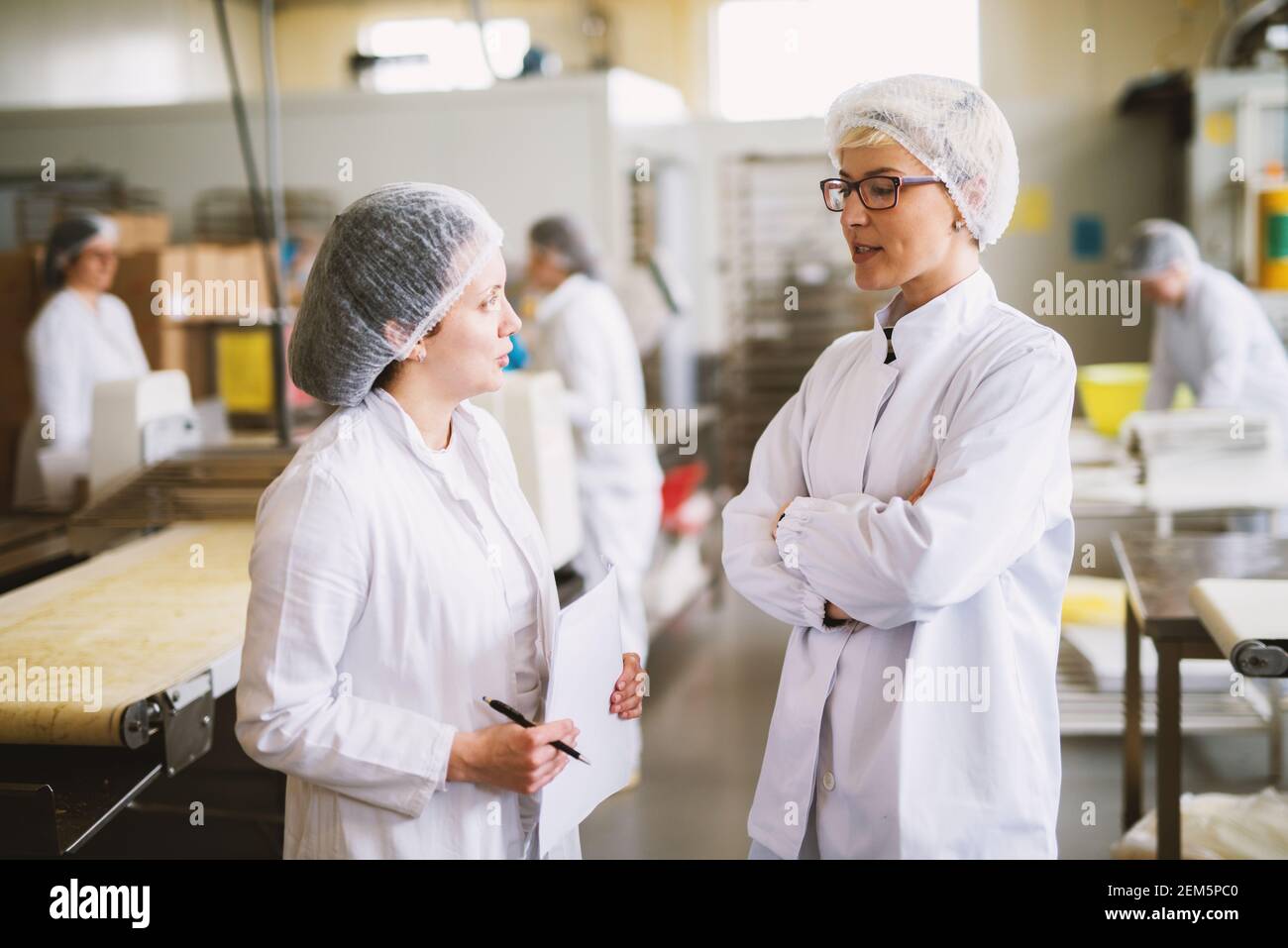 Two dedicated female workers are discussing their daily quota while ...