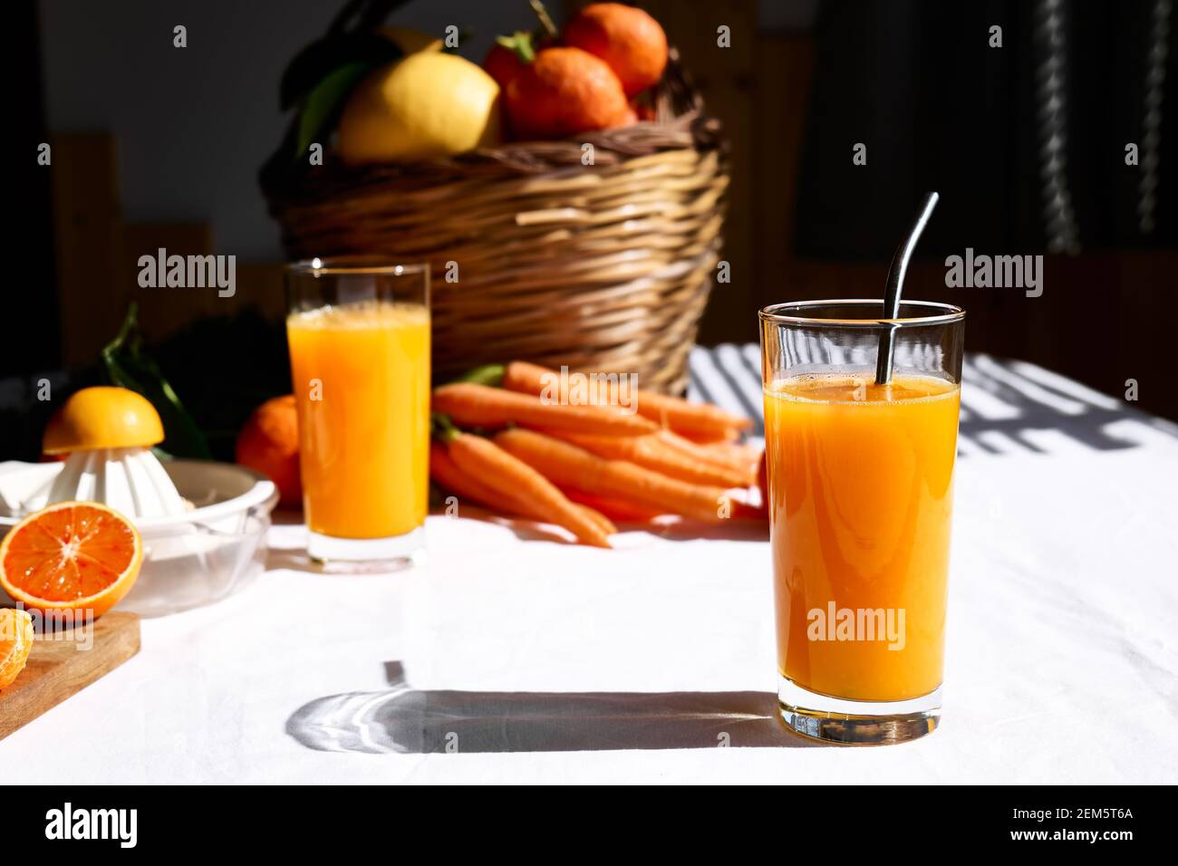 Glass of fresh squeezed orange juice on the table of the kitchen. Ripe ...