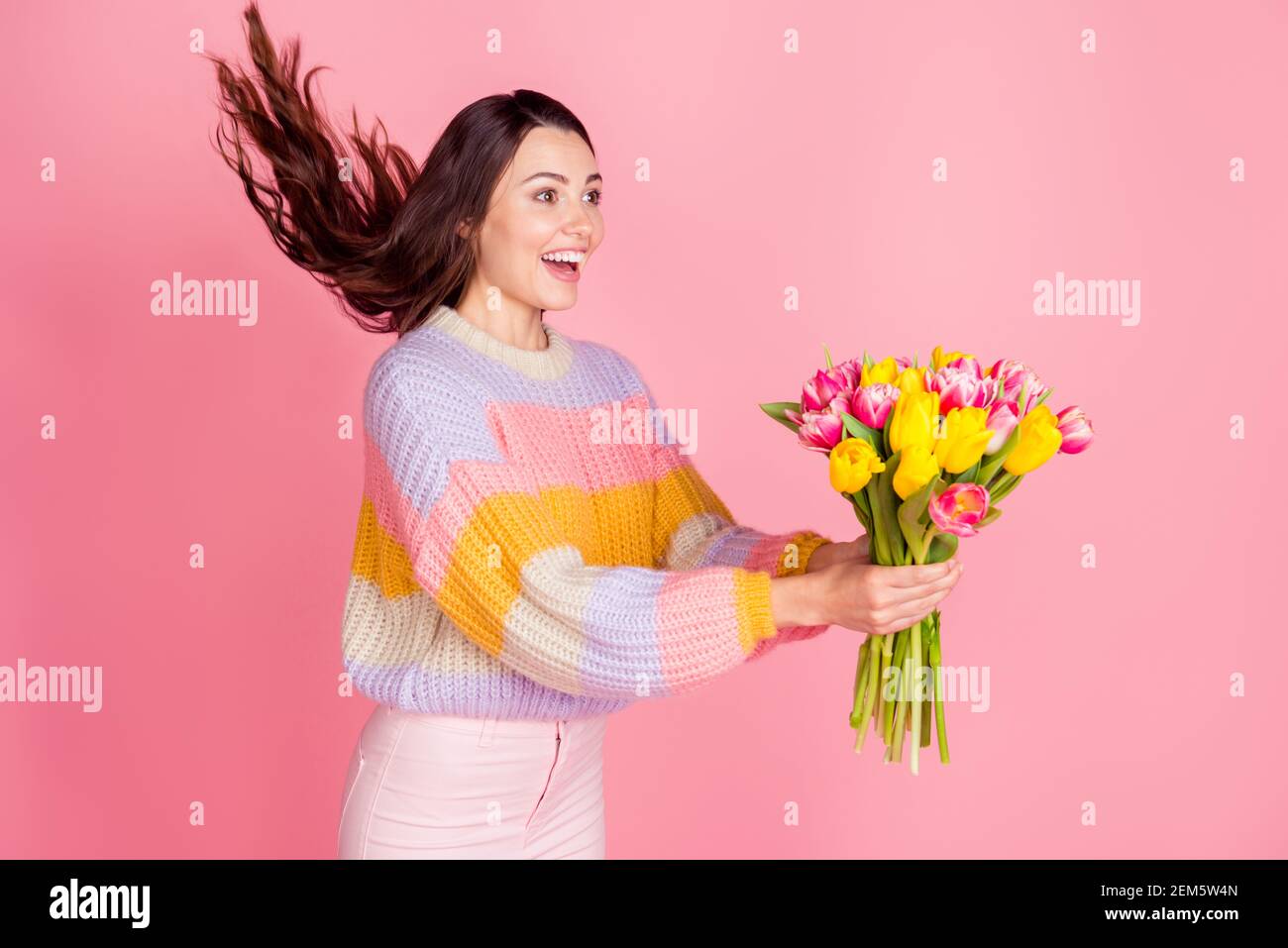 Portrait of pretty trendy cheerful girl getting tulips wind blowing ...