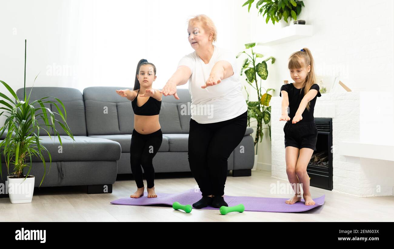 grandmother and children exercising workout at home near the window in ...