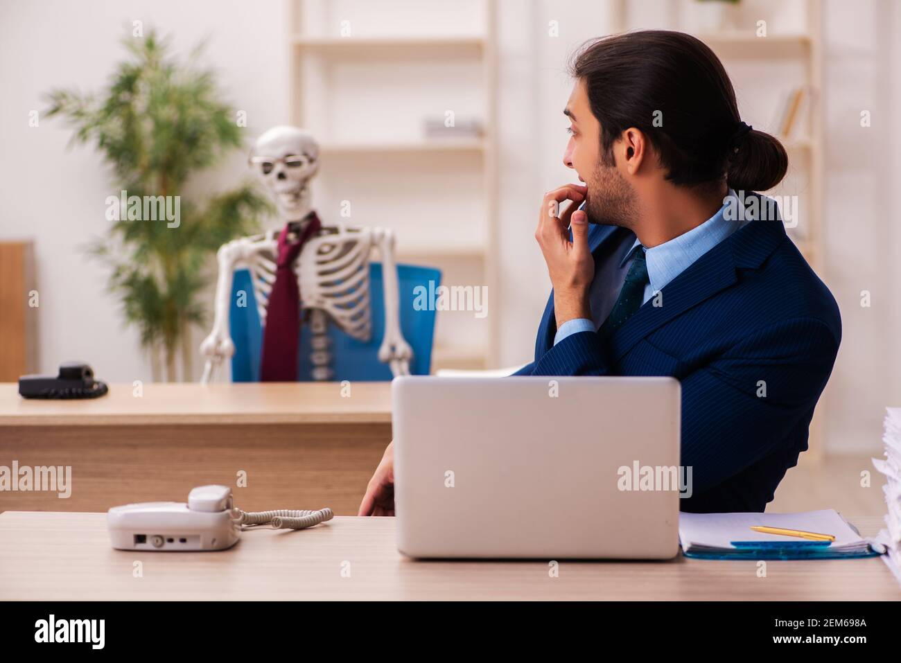 Dead employee working in the office in funny concept Stock Photo - Alamy