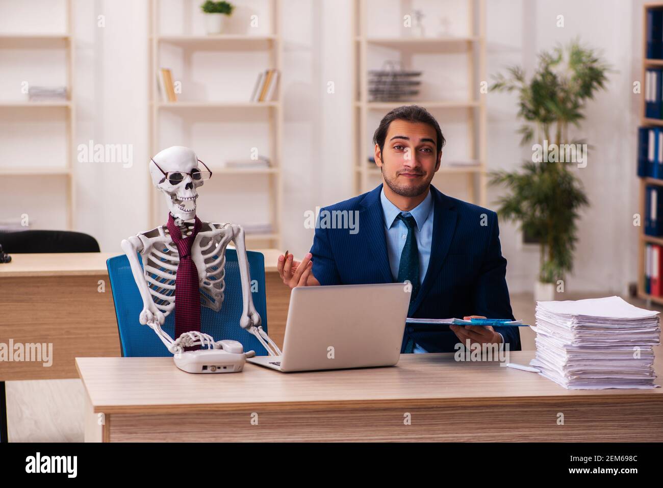 Dead employee working in the office in funny concept Stock Photo - Alamy