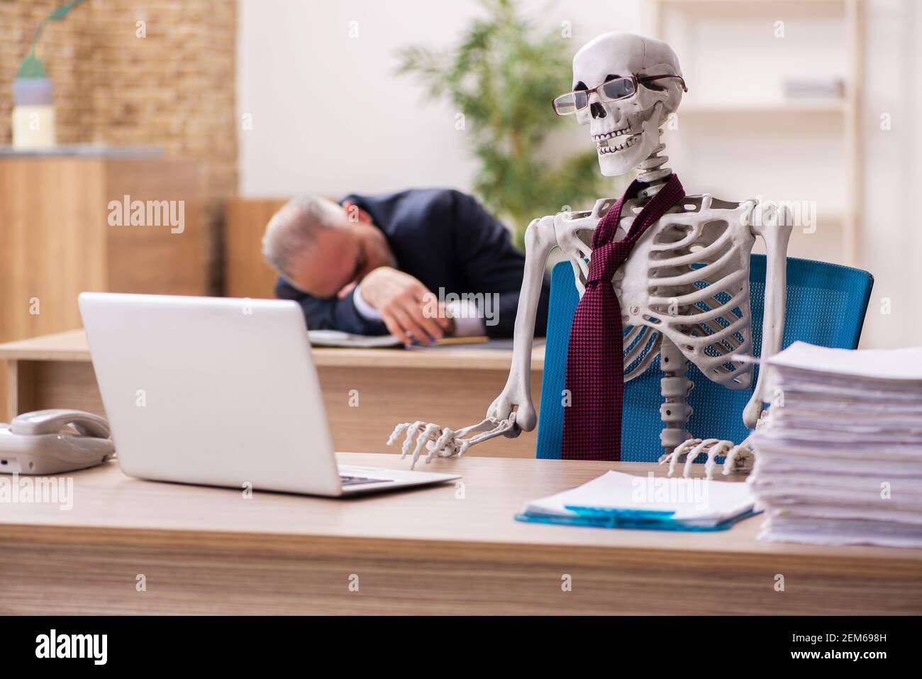 Dead employee working in the office in funny concept Stock Photo - Alamy