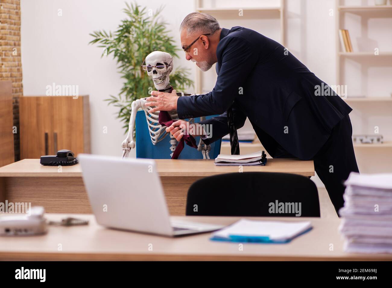 Dead employee working in the office in funny concept Stock Photo - Alamy