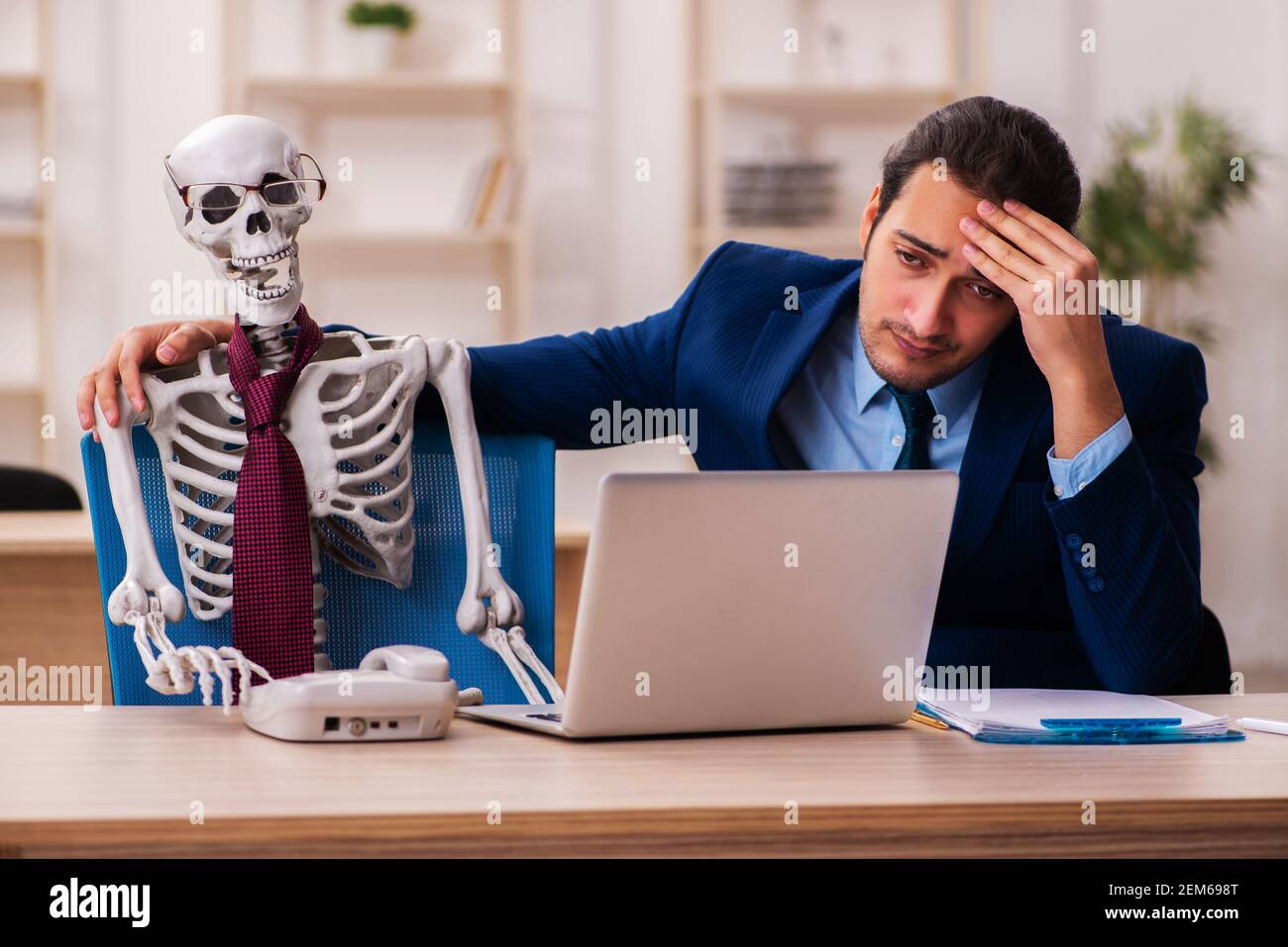 Dead employee working in the office in funny concept Stock Photo - Alamy