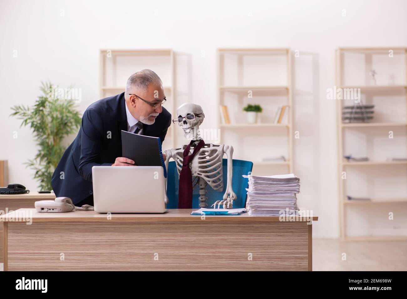 Dead employee working in the office in funny concept Stock Photo - Alamy