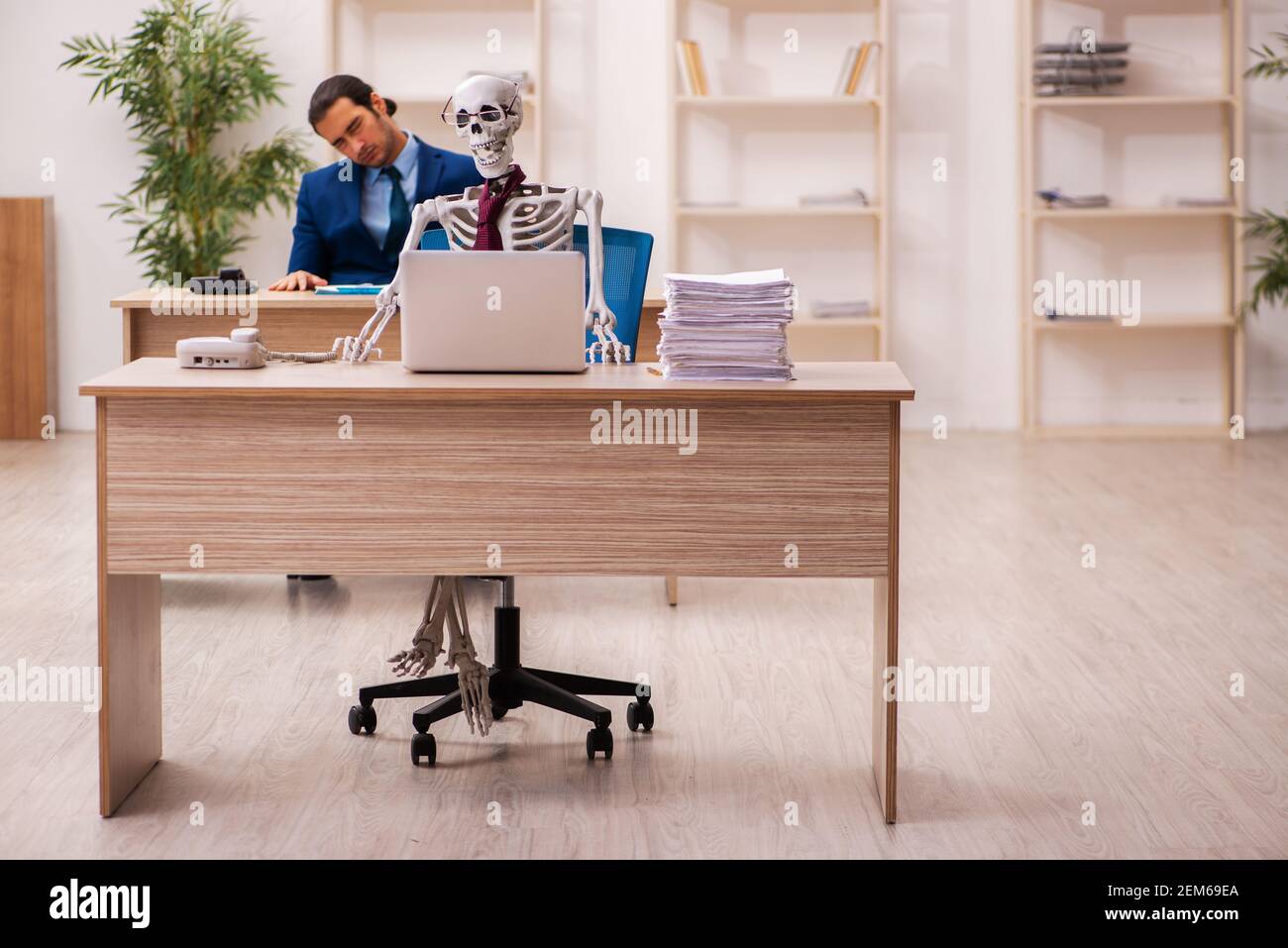 Dead employee working in the office in funny concept Stock Photo - Alamy