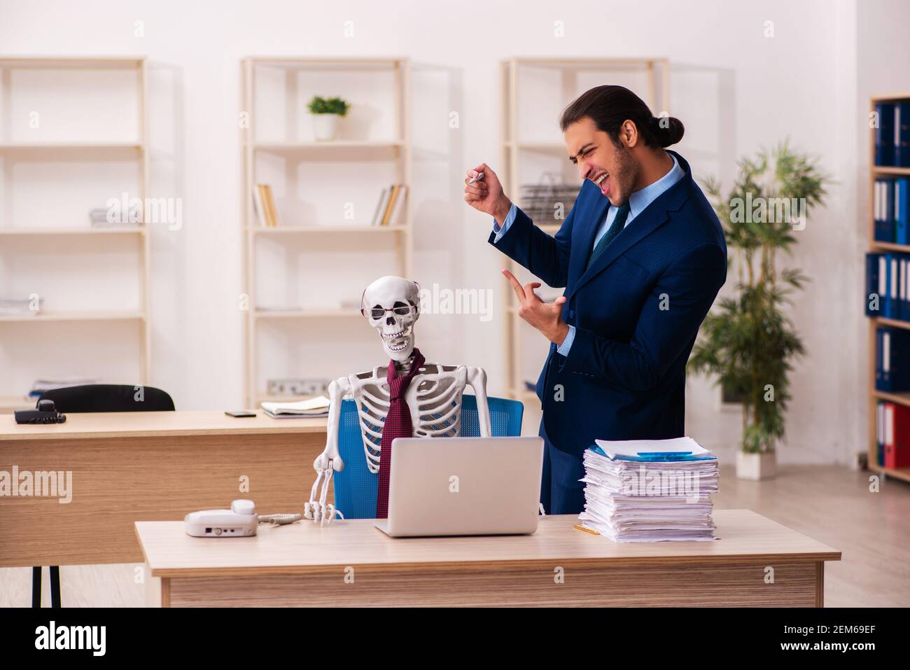 Dead employee working in the office in funny concept Stock Photo - Alamy