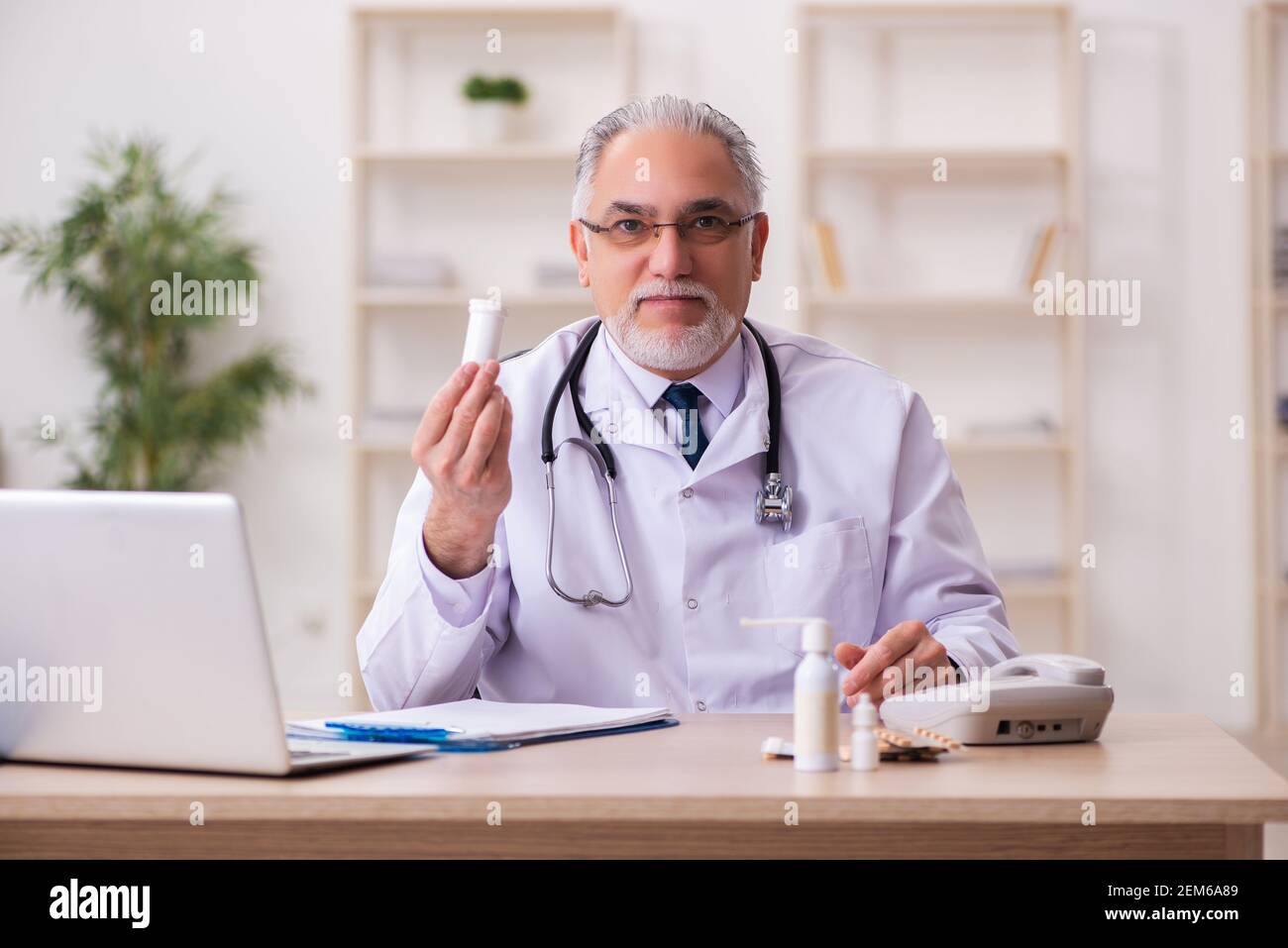 Old male doctor working in the clinic Stock Photo - Alamy