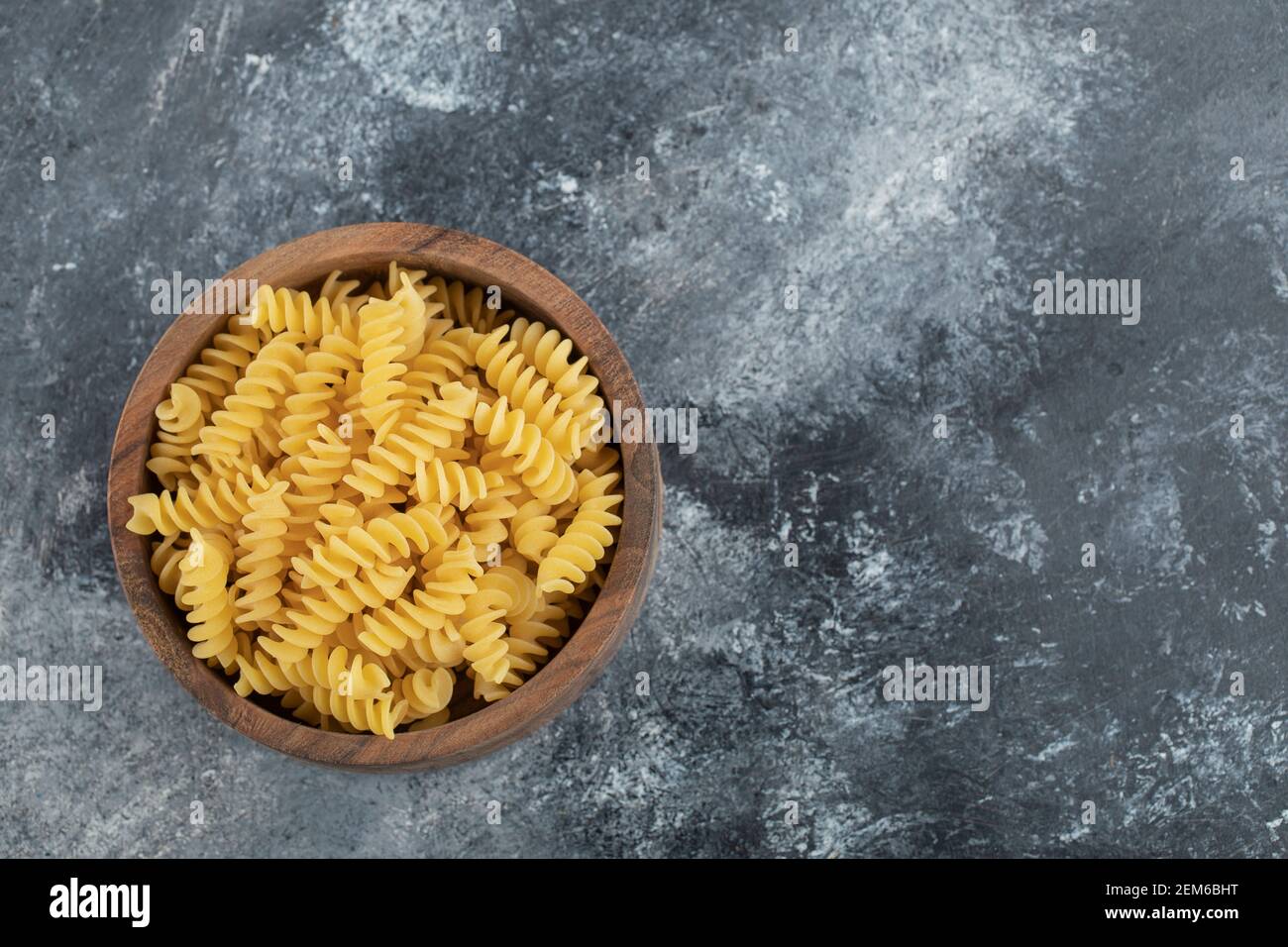 A wooden bowl full of raw dry fusilli pasta Stock Photo - Alamy