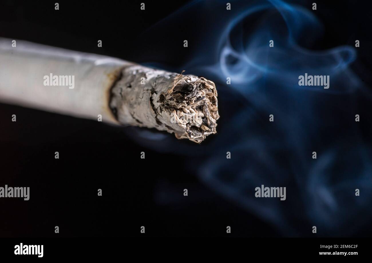 Burning Cigarette with Smoke in a black background Stock Photo - Alamy