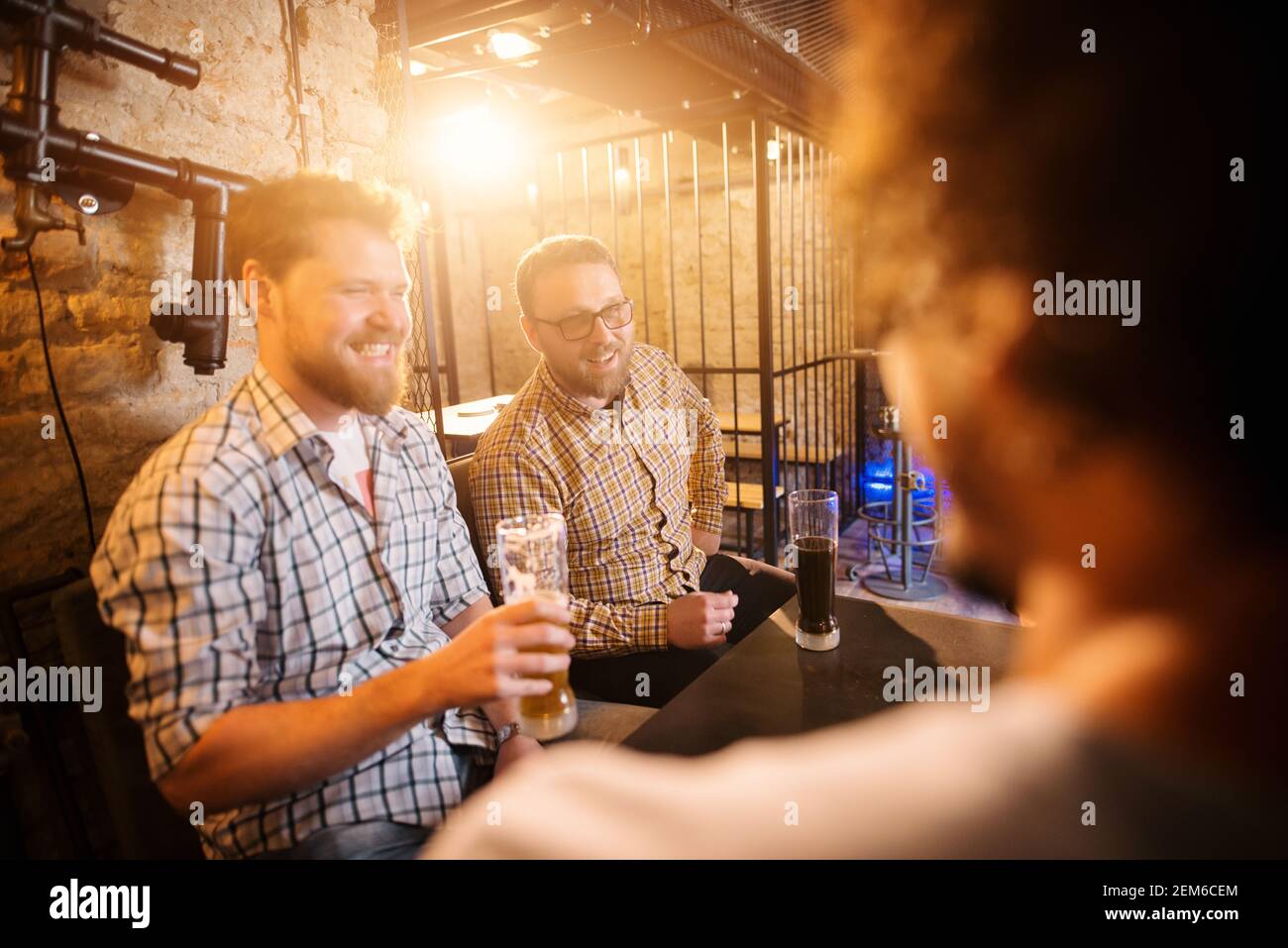Drunk positive male friends relaxing with a draft beer and talking in ...