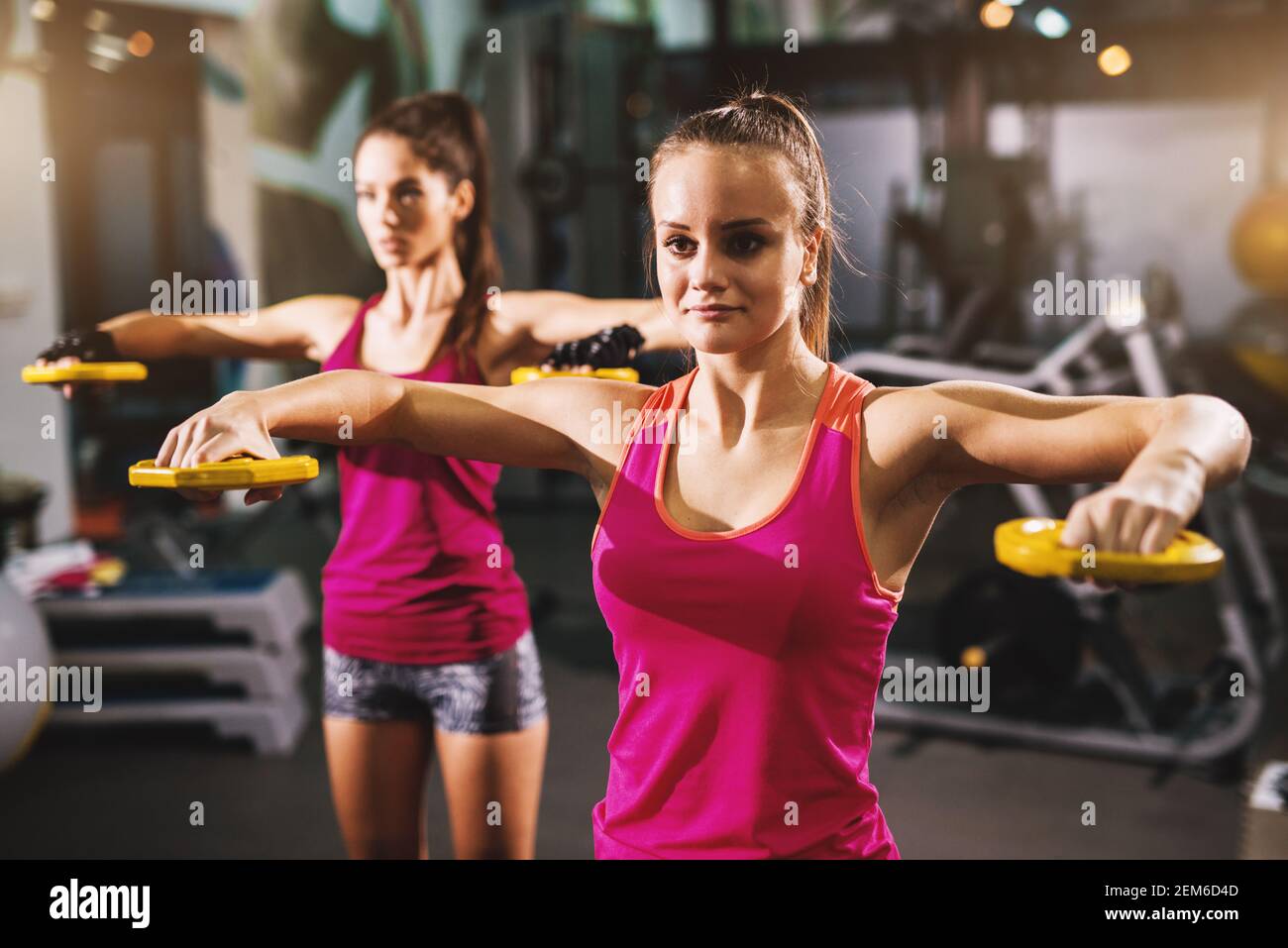 Two adorable charming fit girls are doing exercises with small yellow ...