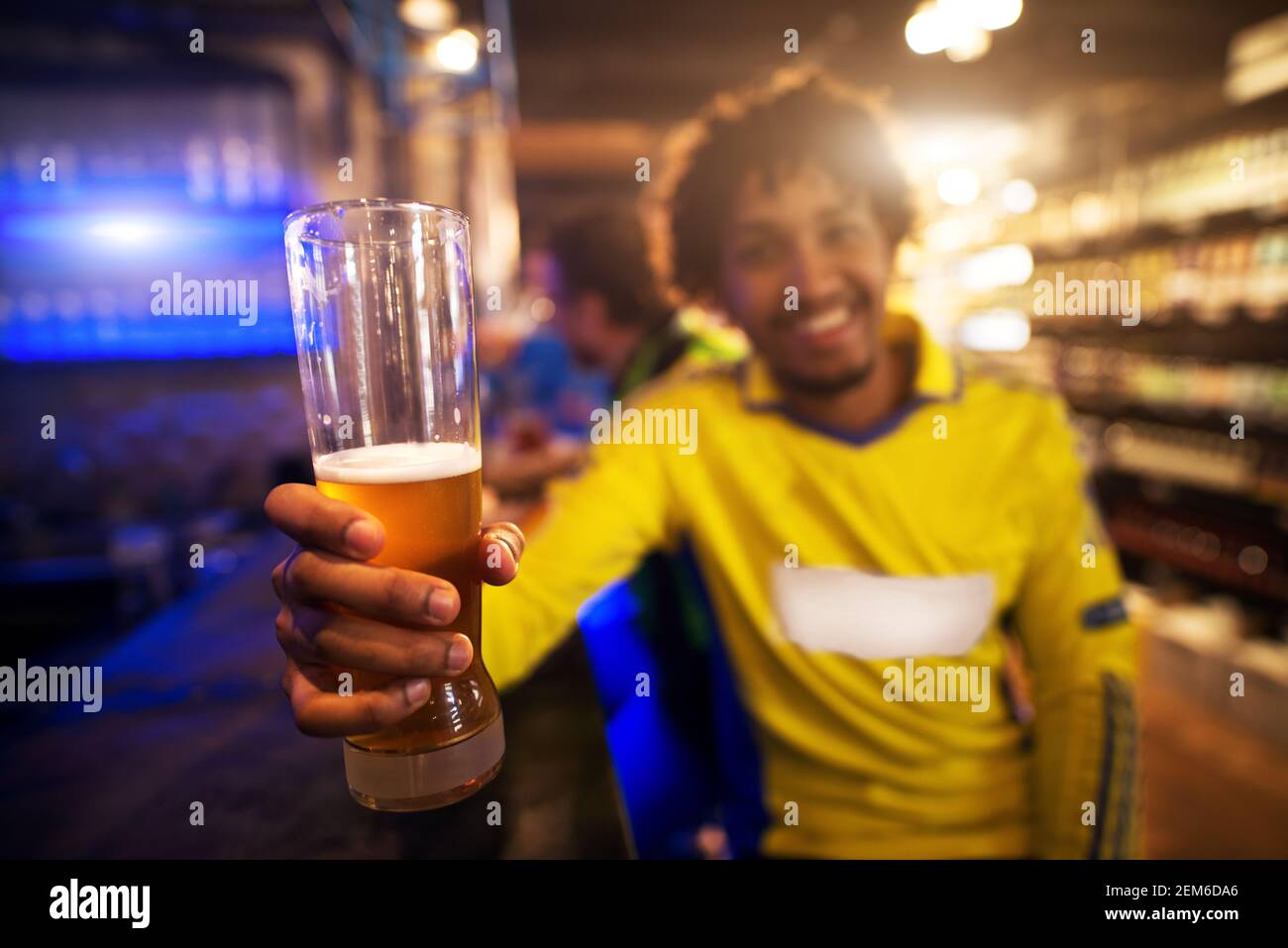 Soccer fan is lifting his beer glass celebrating while sitting at the ...