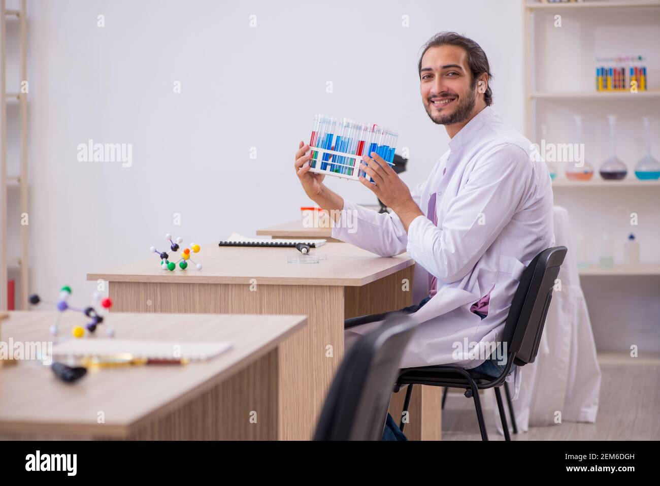 Young chemist sitting at the desk in the classroom Stock Photo - Alamy