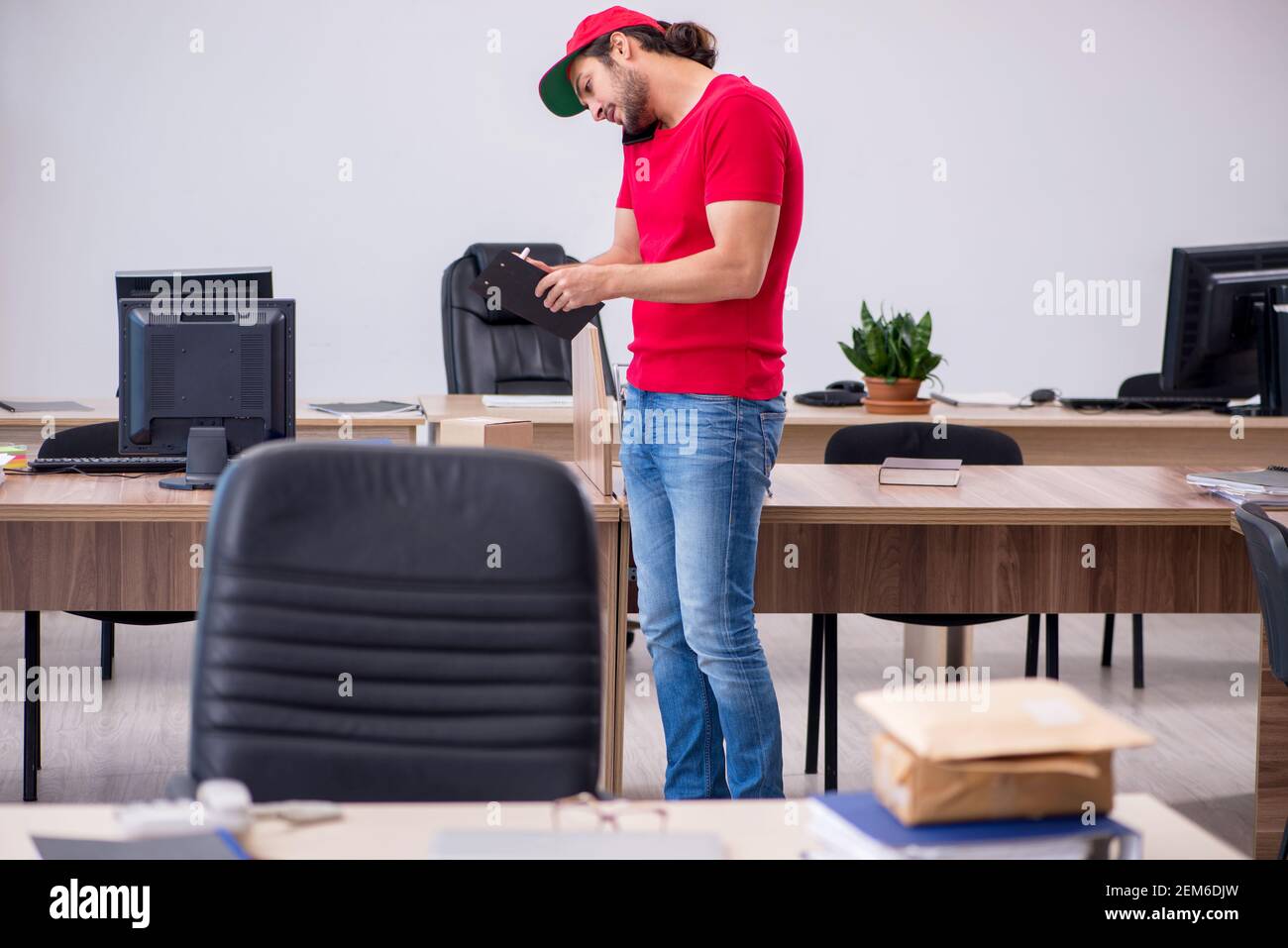 Young courier delivering post to the office Stock Photo - Alamy