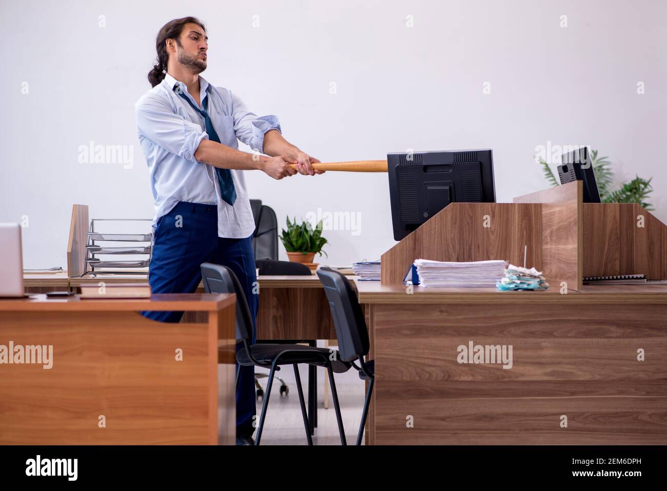 Young furious employee holding baseball bat in the office Stock Photo ...