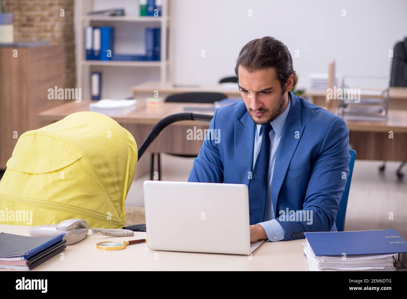 Young male employee looking after new born in the office Stock Photo ...