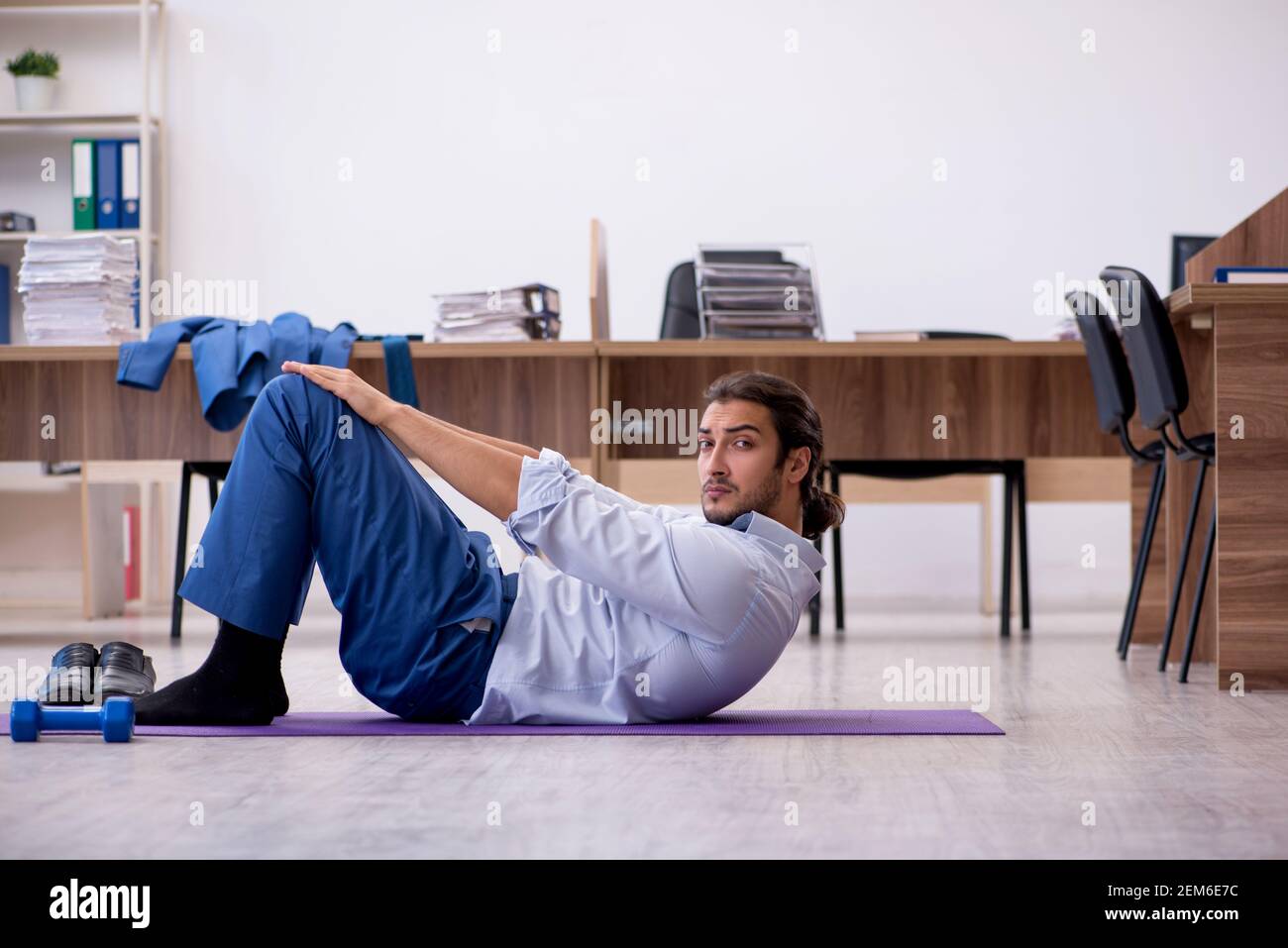 Young employee doing sport exercises during break Stock Photo - Alamy