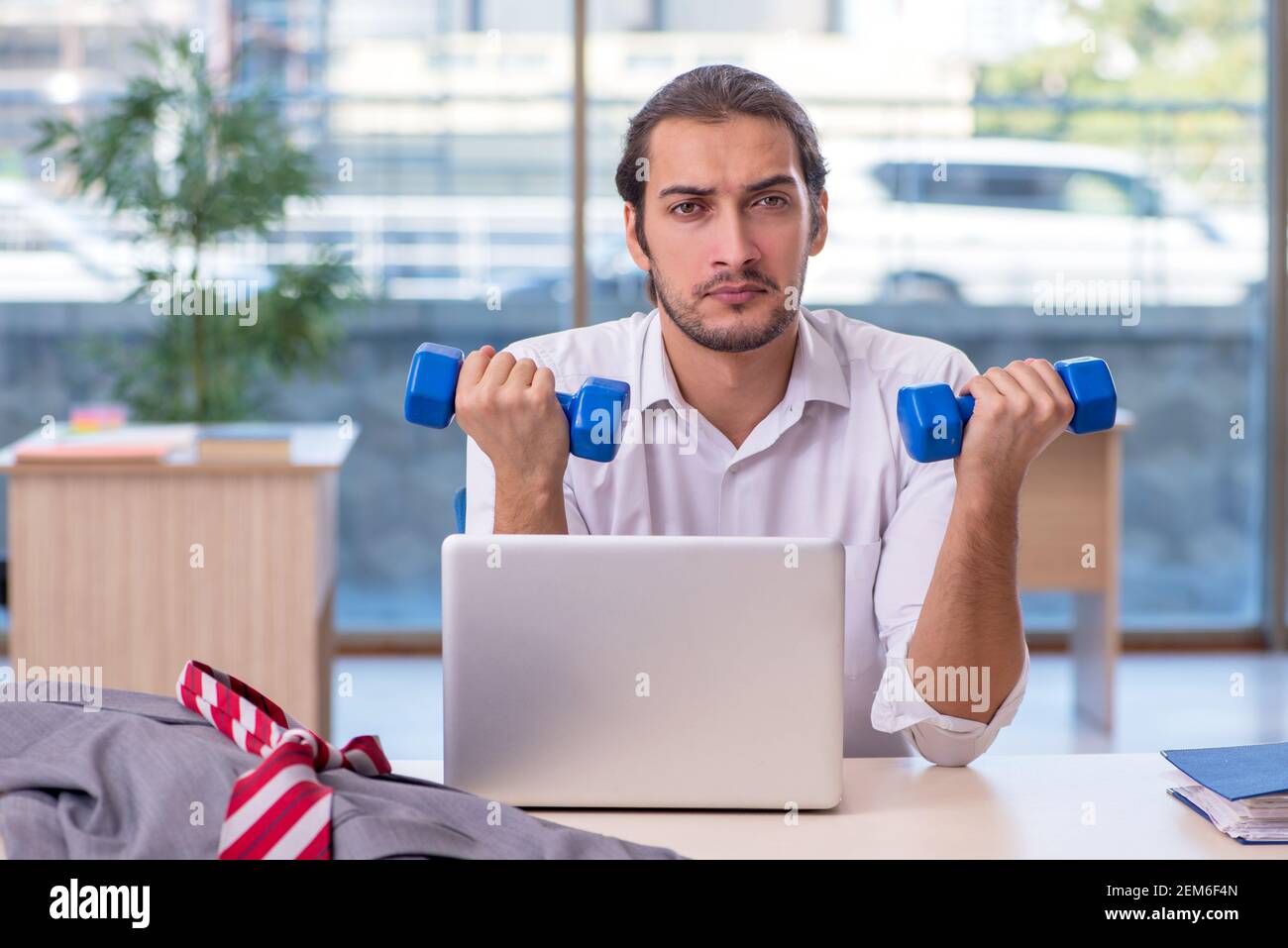 Young employee doing sport exercises at workplace Stock Photo - Alamy