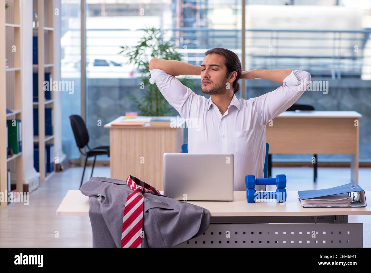 Young employee doing sport exercises at workplace Stock Photo - Alamy