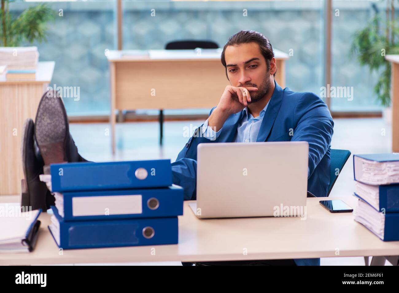 Young employee and too much work in the office Stock Photo - Alamy
