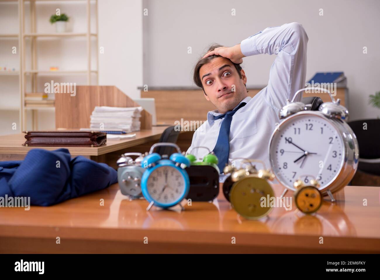 Young businessman sleeping in the office in time management concept ...
