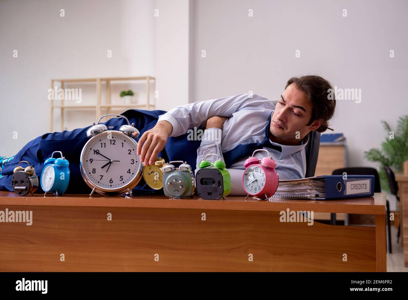 Young businessman sleeping in the office in time management concept ...