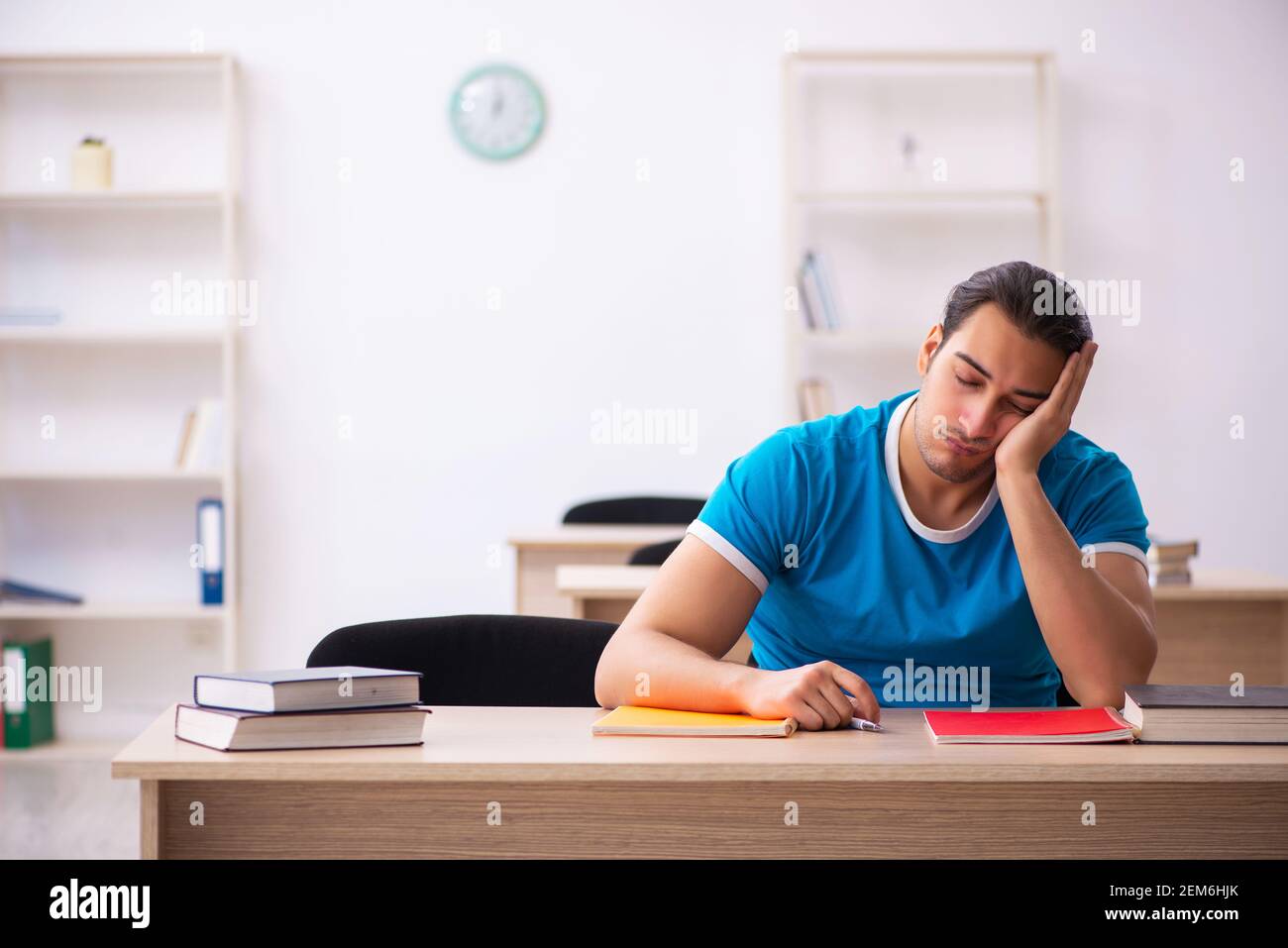 Exhausted student preparing for the exams in the classroom Stock Photo ...