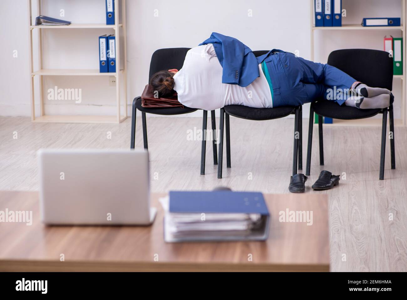 Young employee sleeping in the office on chairs Stock Photo - Alamy