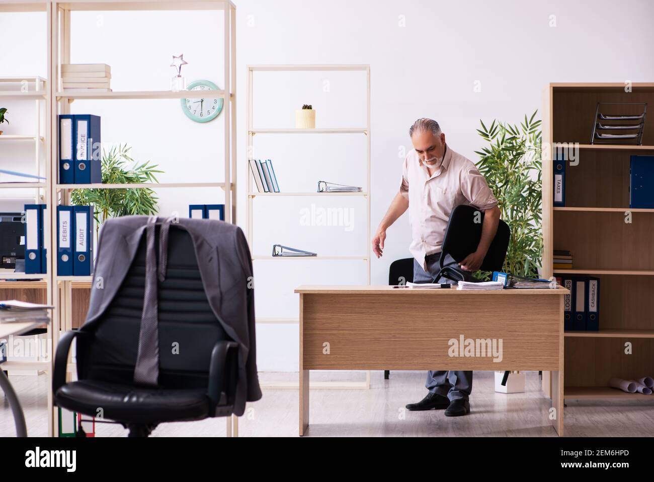 Senior male employee doing physical exercises at workplace Stock Photo ...