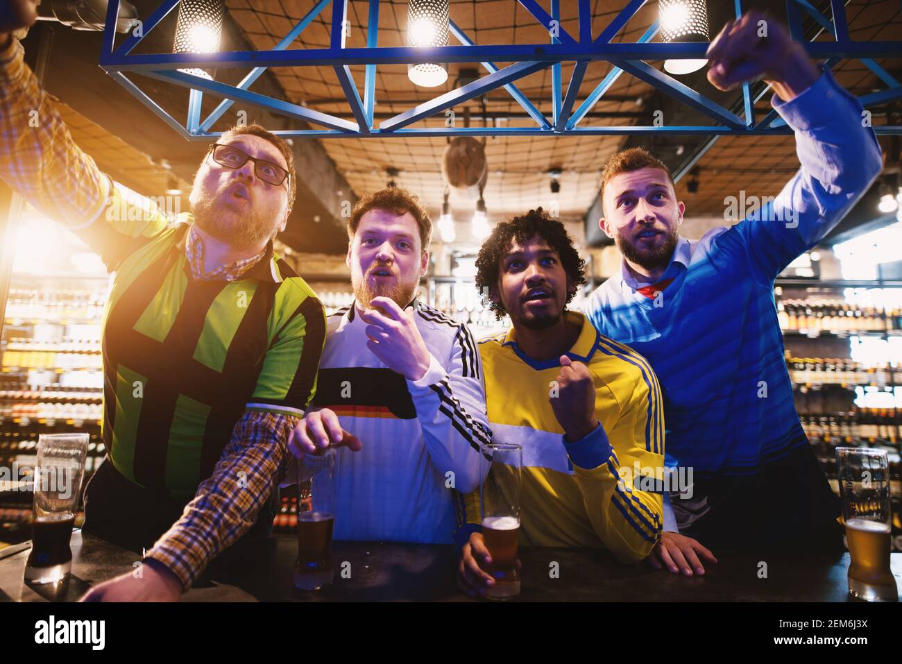 Passionate soccer fans in local pub are cheering for their team to ...