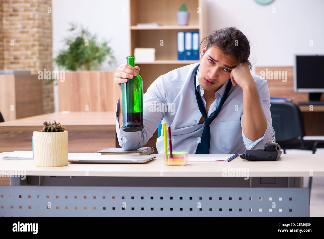 Male employee drinking alcohol at workplace Stock Photo - Alamy