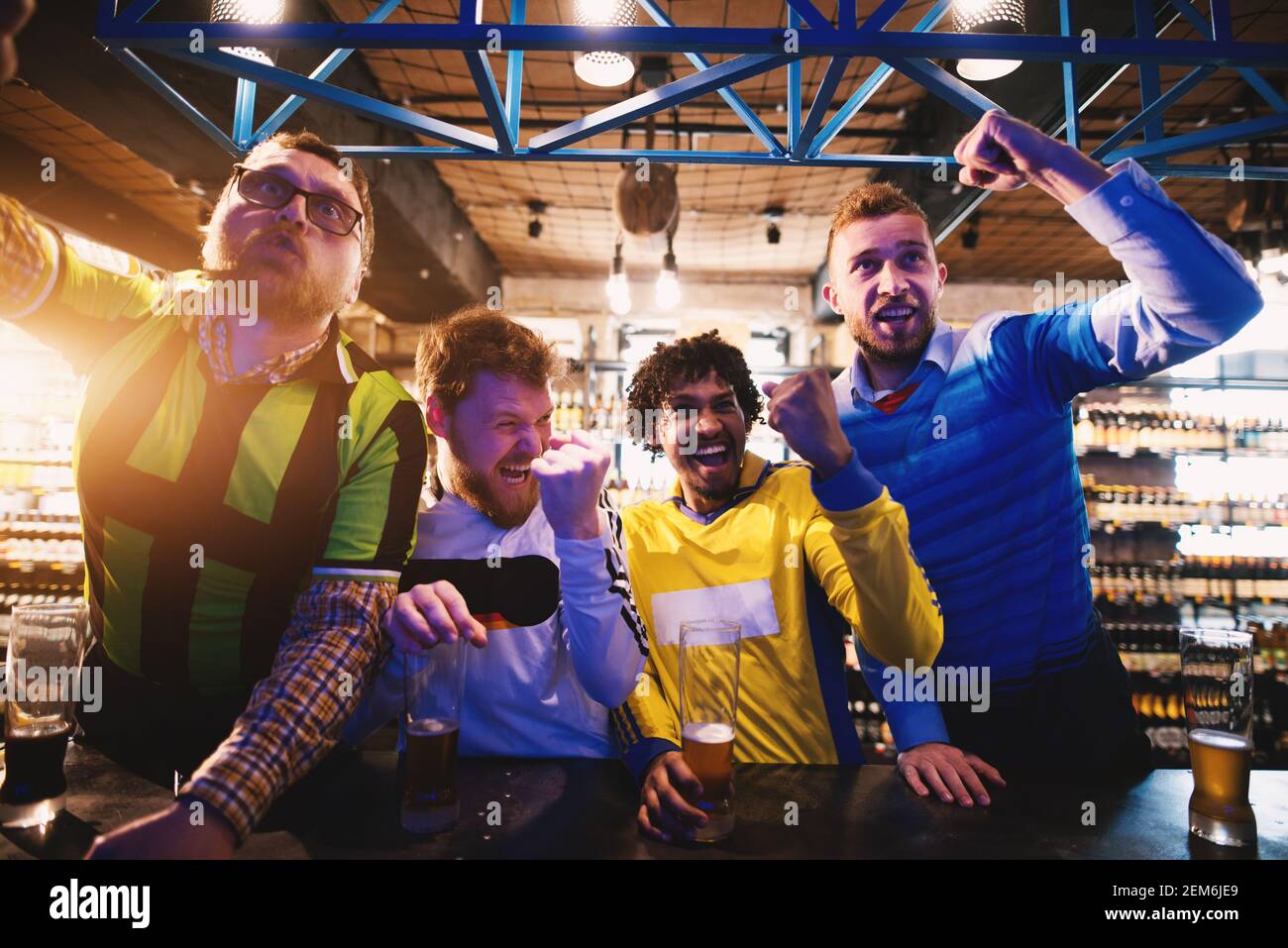Passionate football fans are sitting at the counter of dimmed pub and ...