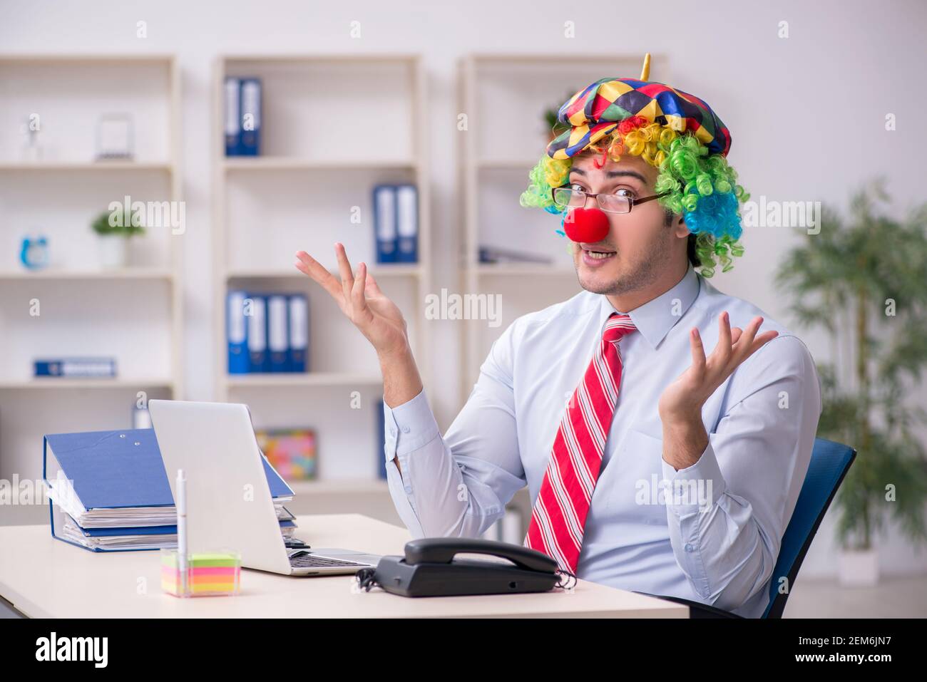 Funny employee clown working in the office room Stock Photo - Alamy