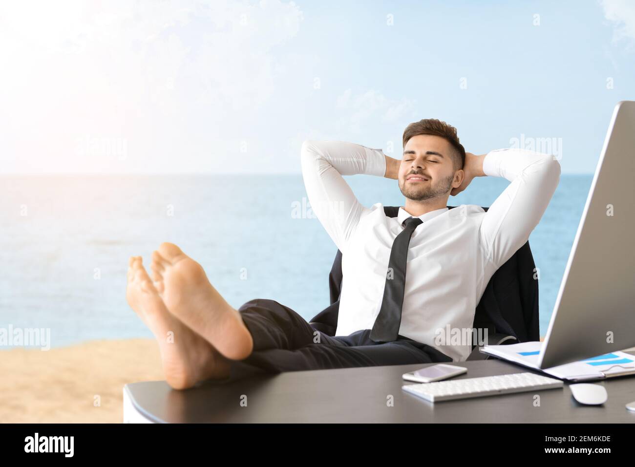 Handsome young businessman relaxing at workplace on beach Stock Photo ...