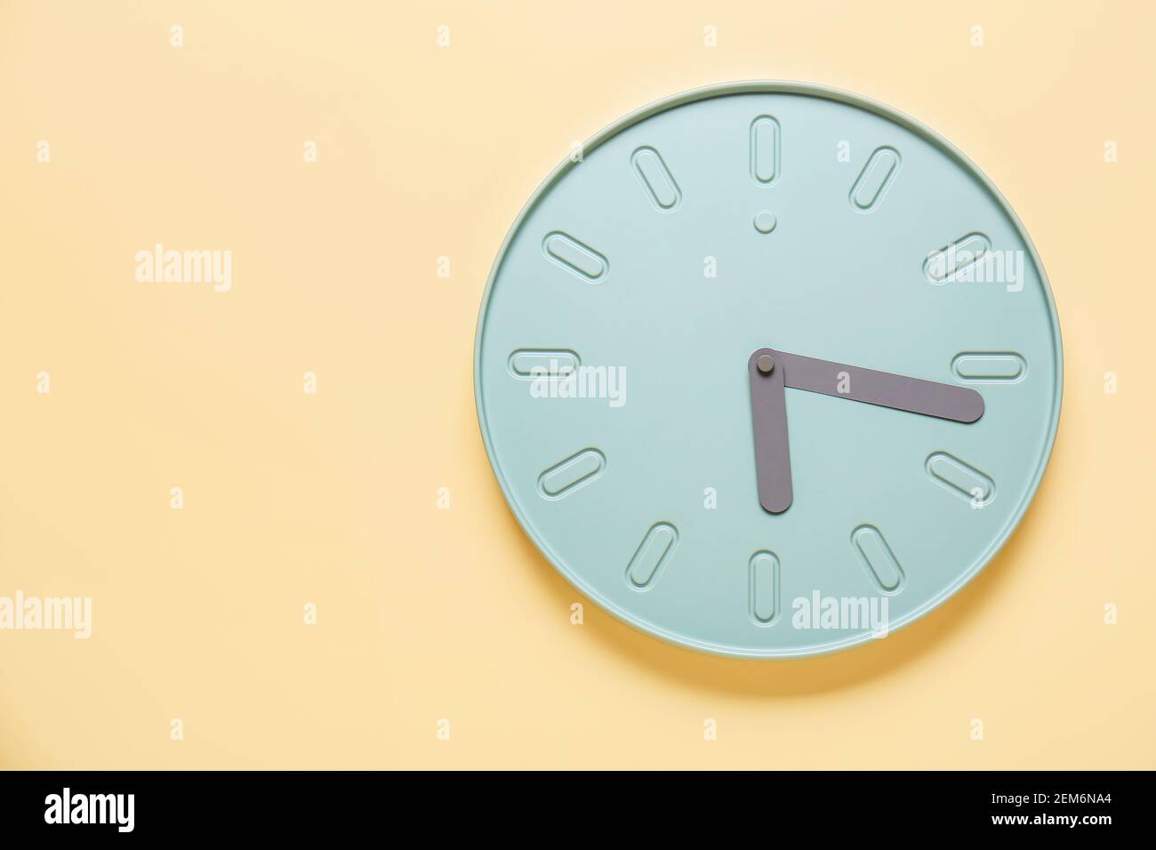 Stylish clock hanging on color wall Stock Photo - Alamy