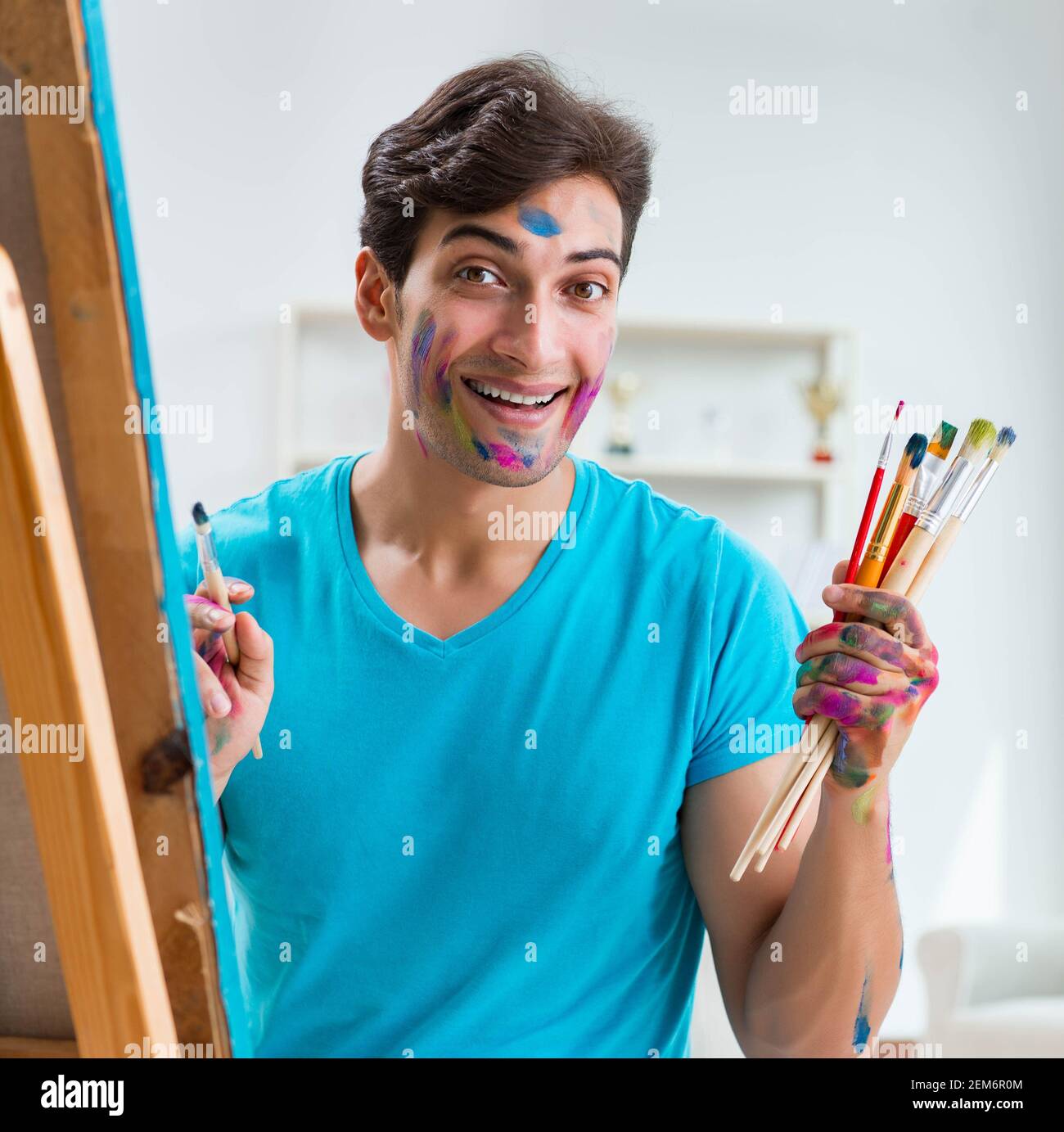 The young funny artist working on new painting in his studio Stock ...